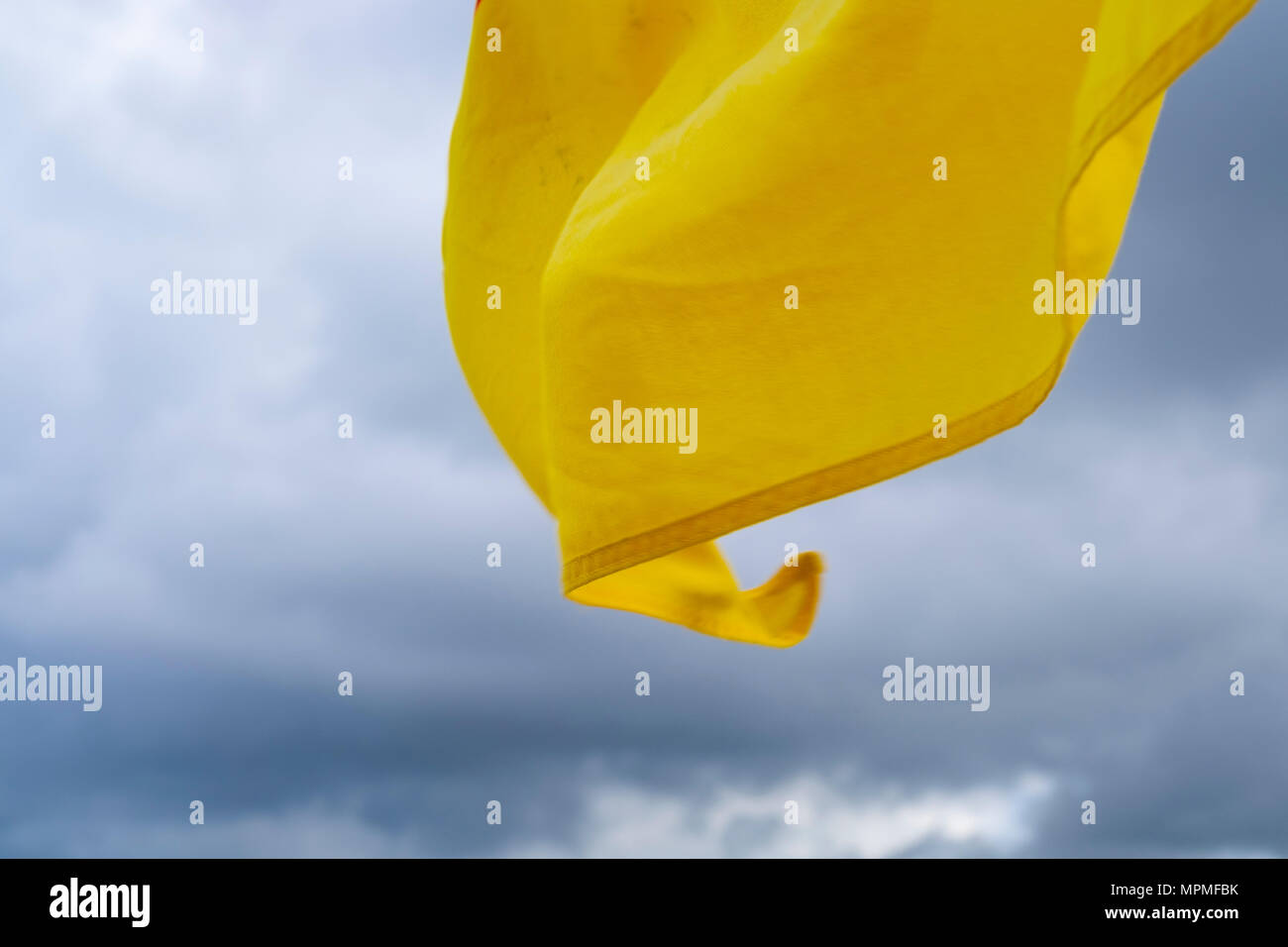Red & Yellow RNLI Safety Flags on the beach with cloudy blue skies ...