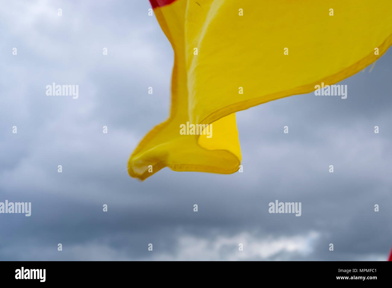Red & Yellow RNLI Safety Flags on the beach with cloudy blue skies ...