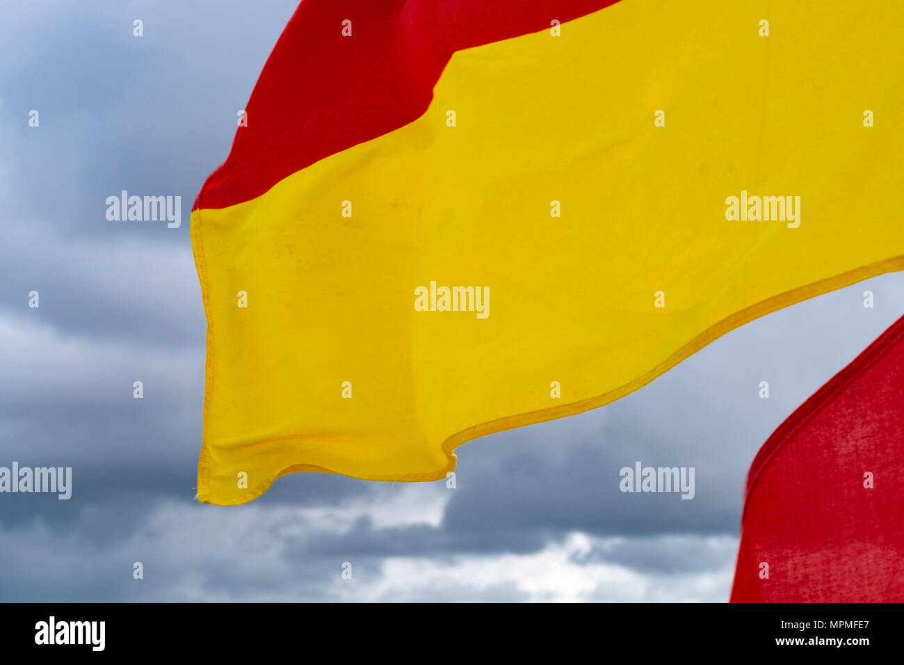 Red & Yellow RNLI Safety Flags on the beach with cloudy blue skies ...