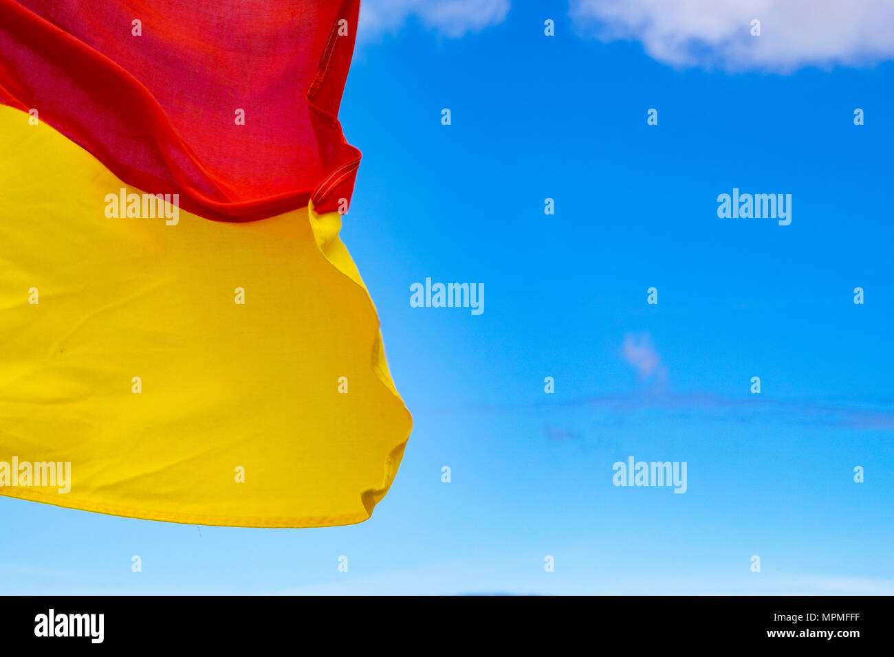 Red & Yellow RNLI Safety Flags on the beach with cloudy blue skies ...