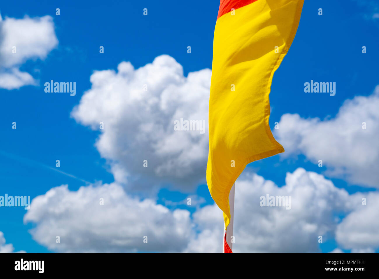 Red & Yellow RNLI Safety Flags on the beach with cloudy blue skies ...