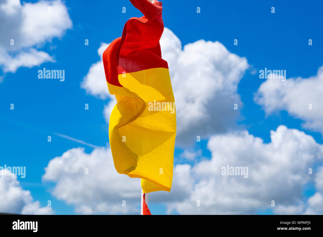 Red & Yellow RNLI Safety Flags on the beach with cloudy blue skies ...