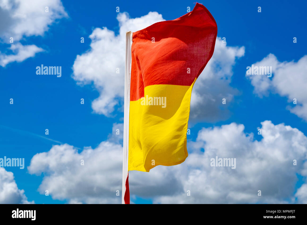 Red & Yellow RNLI Safety Flags on the beach with cloudy blue skies ...