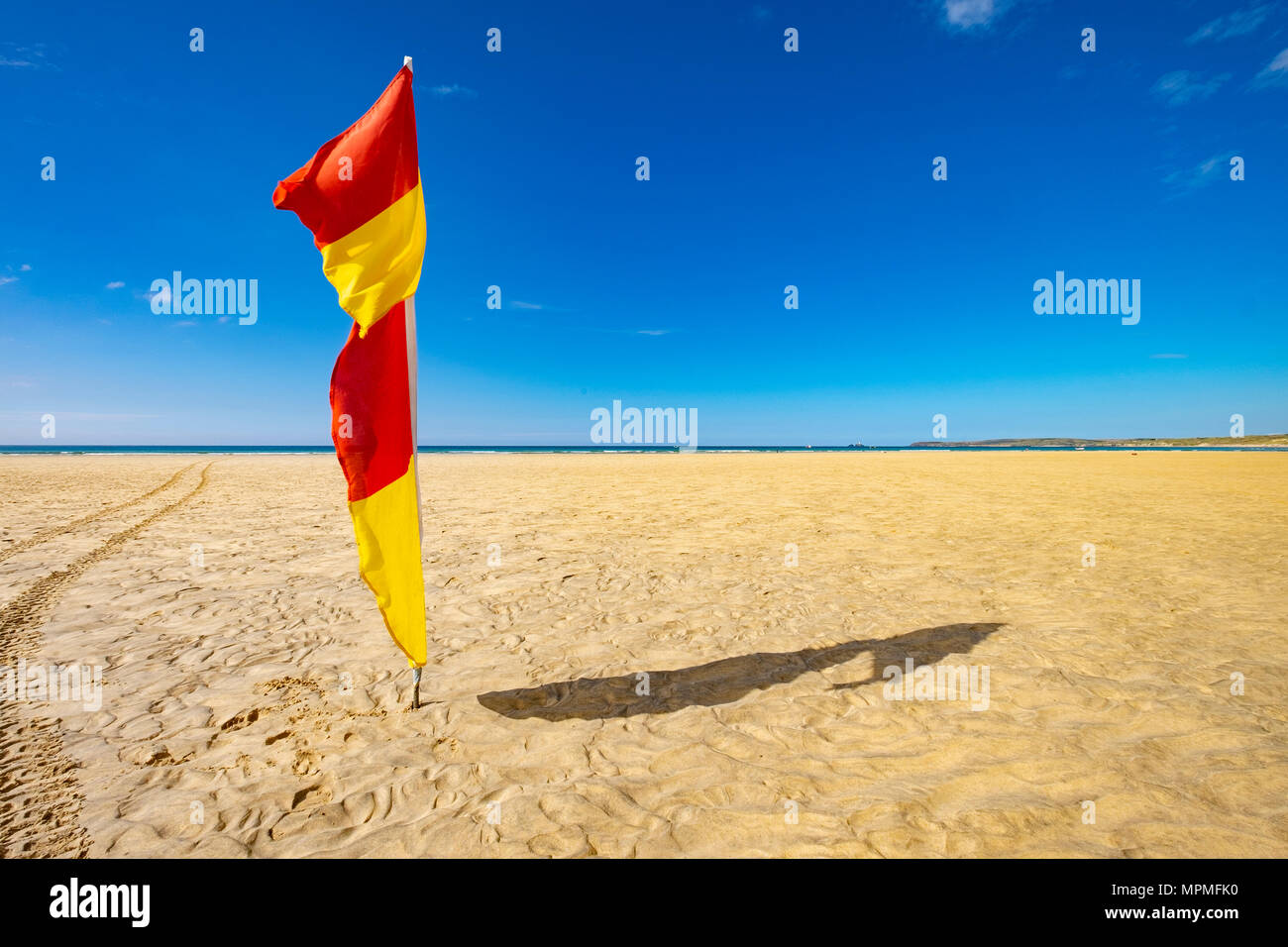 Red & Yellow RNLI Safety Flags on the beach with cloudy blue skies ...