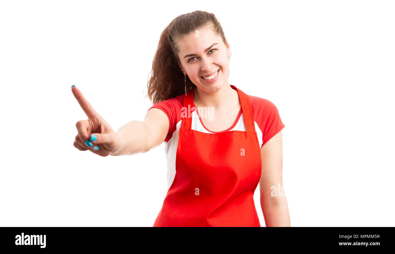 Cheerful female supermarket employee pointing with index finger as ...