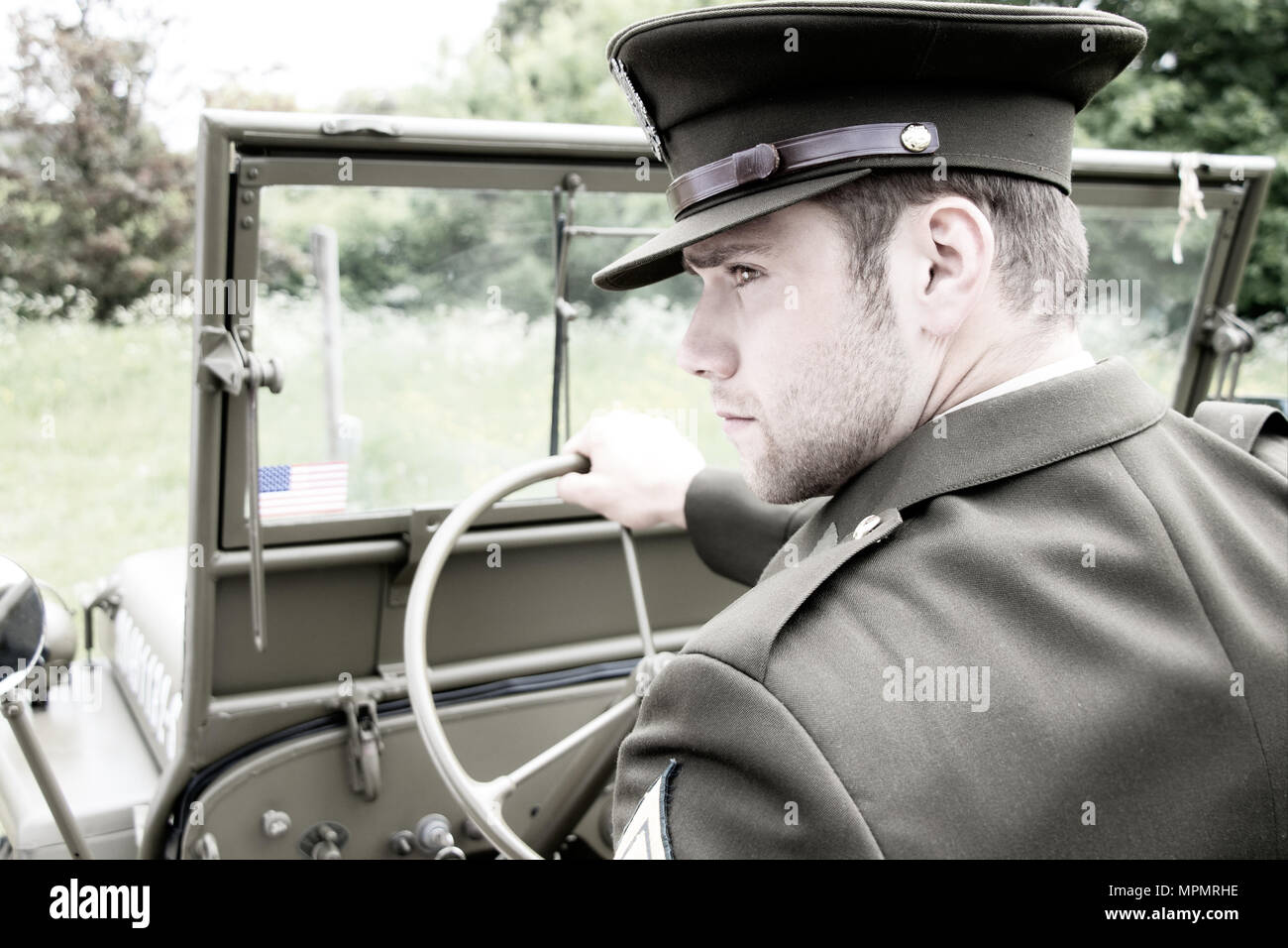 Handsome American WWII GI Army officer in uniform riding military truck ...