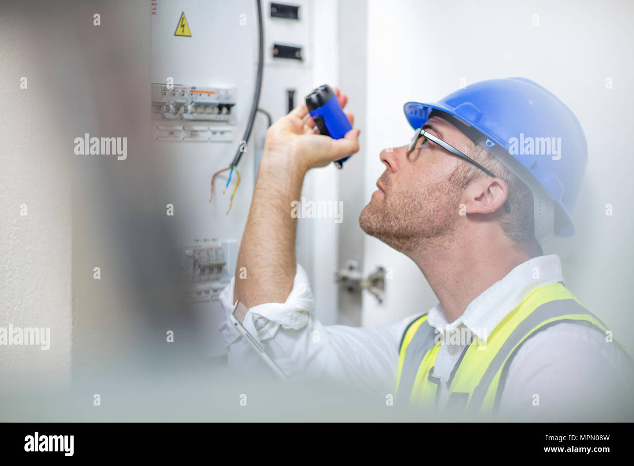 Electrician with flashlight at fusebox Stock Photo - Alamy