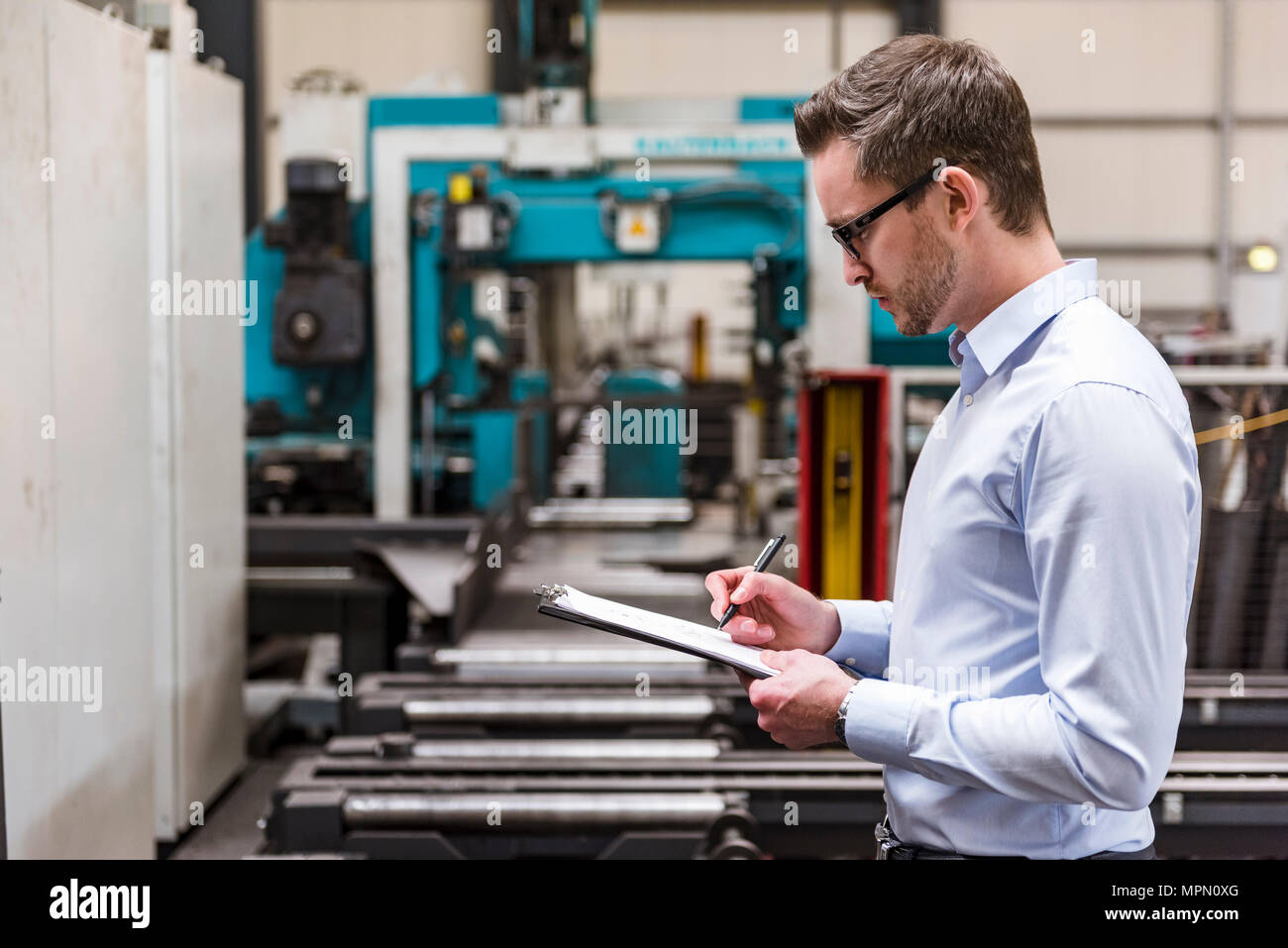 Man writing on clipboard on factory shop floor Stock Photo - Alamy
