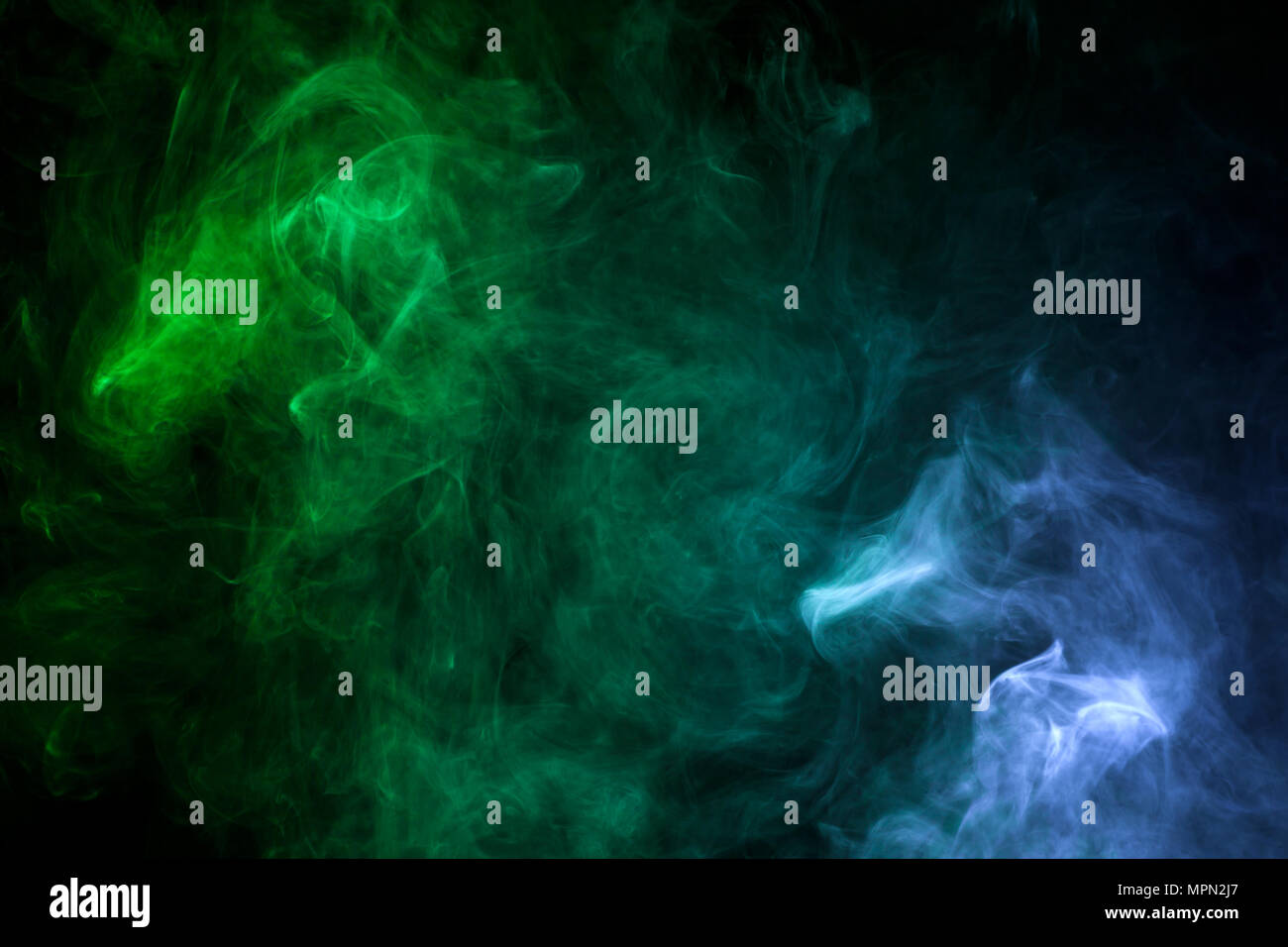 Dense multicolored smoke of green and blue colors on a black isolated ...