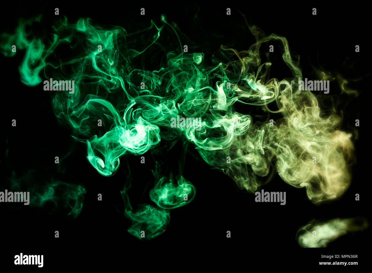 Dense multicolored smoke of green and yellow colors on a black isolated ...