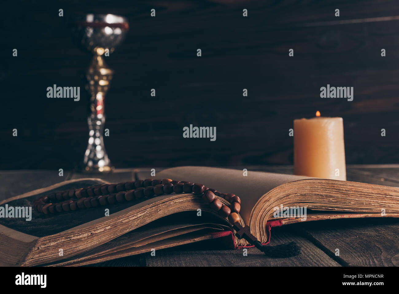 open holy bible with rosary, chalice and candle on wooden table, Holy ...