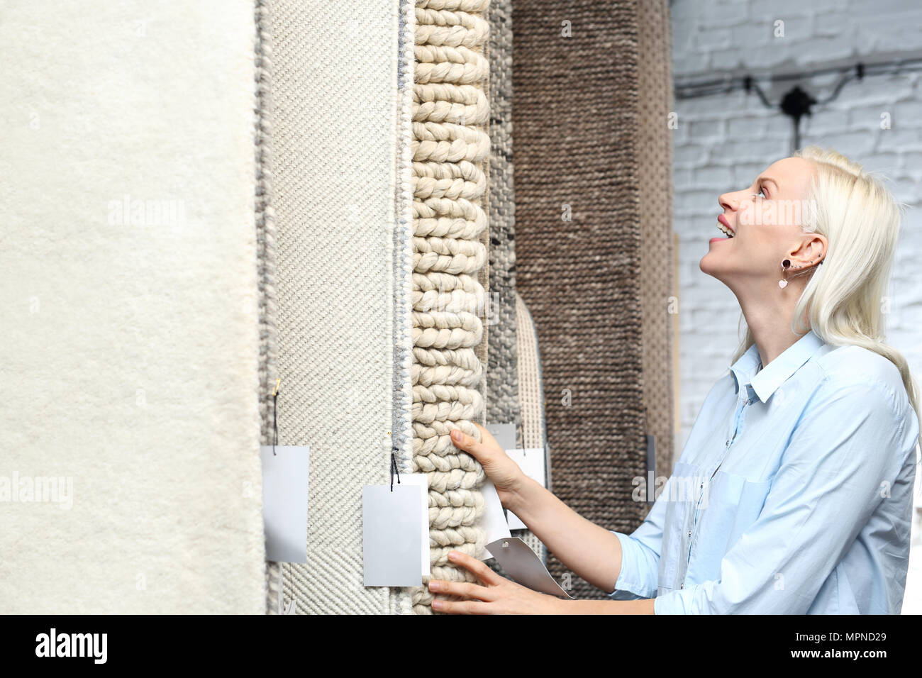 Buying a rug. The woman is watching the carpets in the store with ...