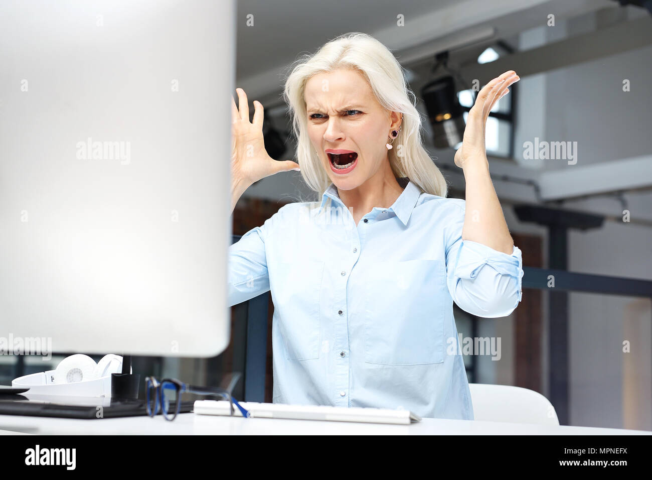 Nerves and anger at work. Furious young woman is irritated at work ...