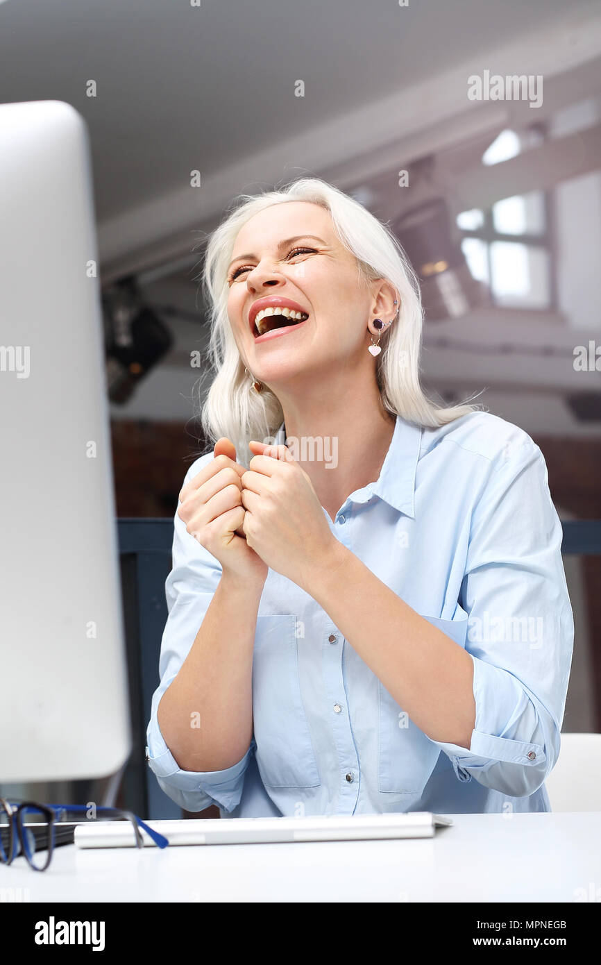 Success in business. A very happy woman is laughing while sitting at a ...