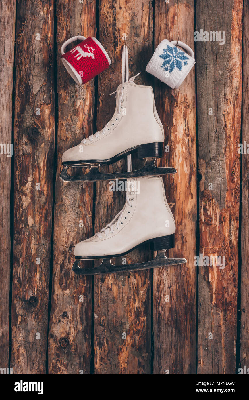 two cups and pair of white skates hanging on wooden wall Stock Photo ...