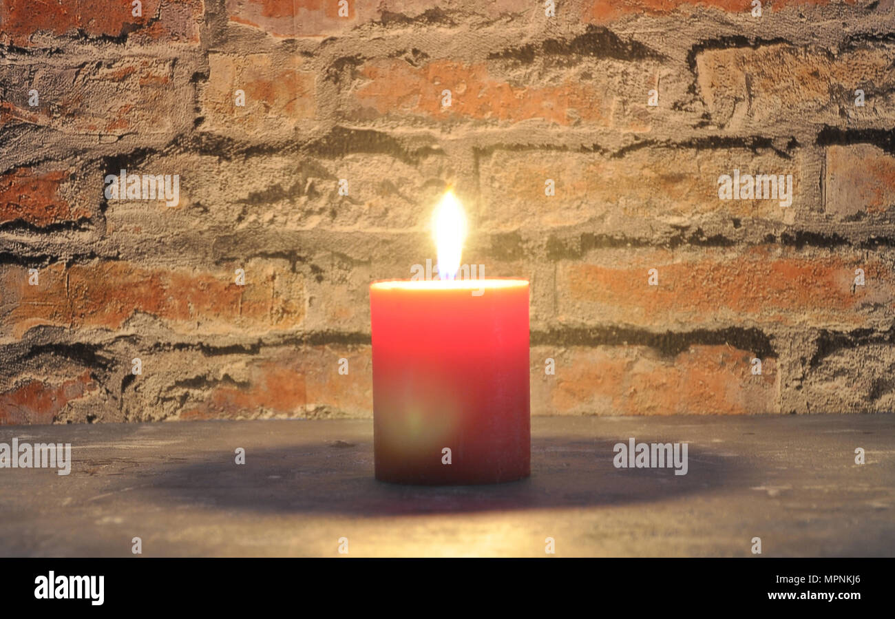 Burning candle in front of brick wall Stock Photo - Alamy