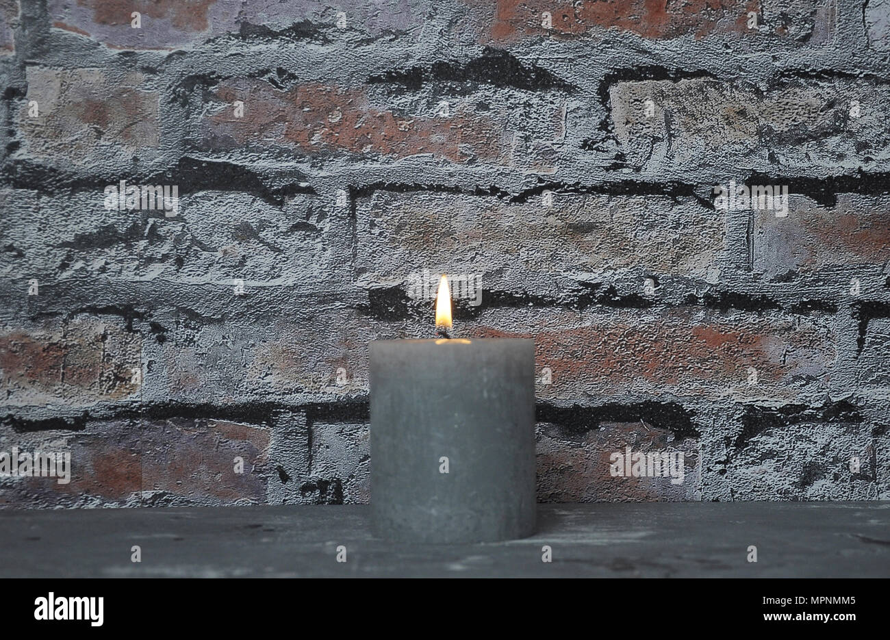 Burning candle in front of brick wall Stock Photo - Alamy