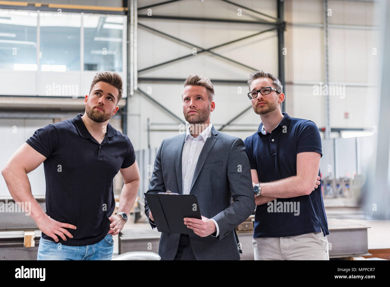 Three men on factory shop floor looking around Stock Photo - Alamy