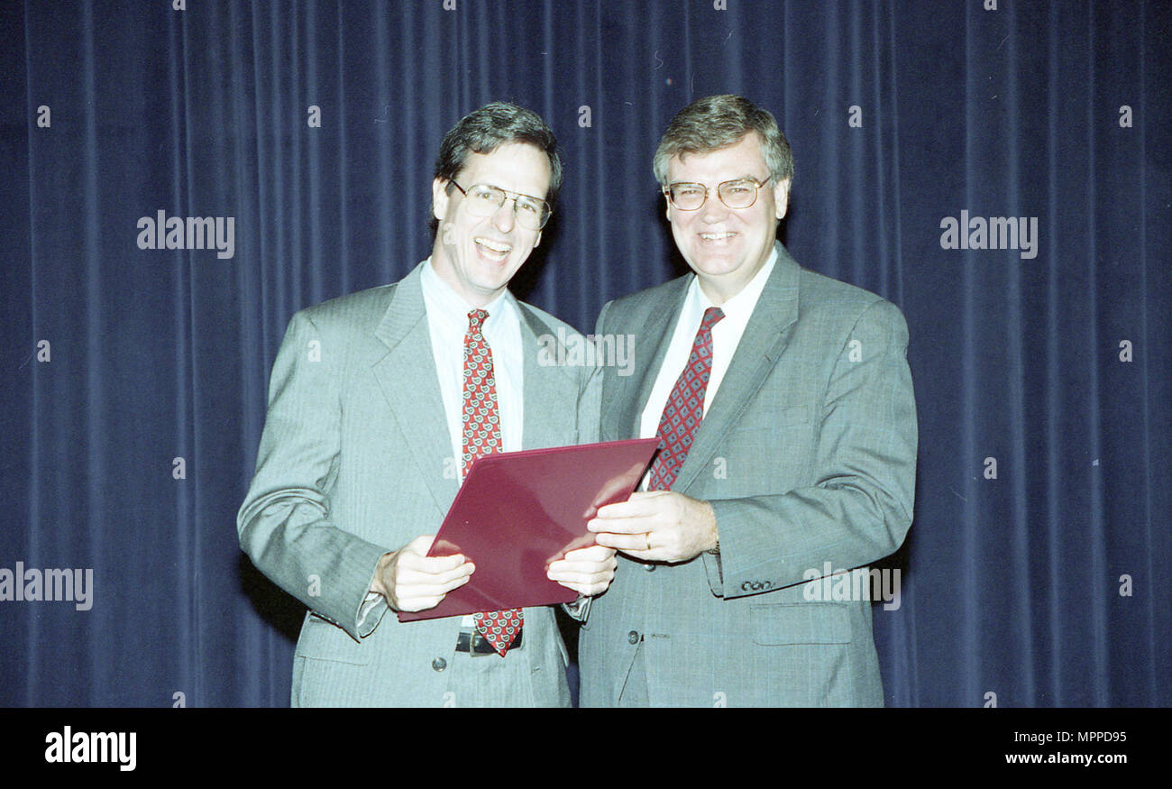 Two men holding an awards certificate Stock Photo - Alamy