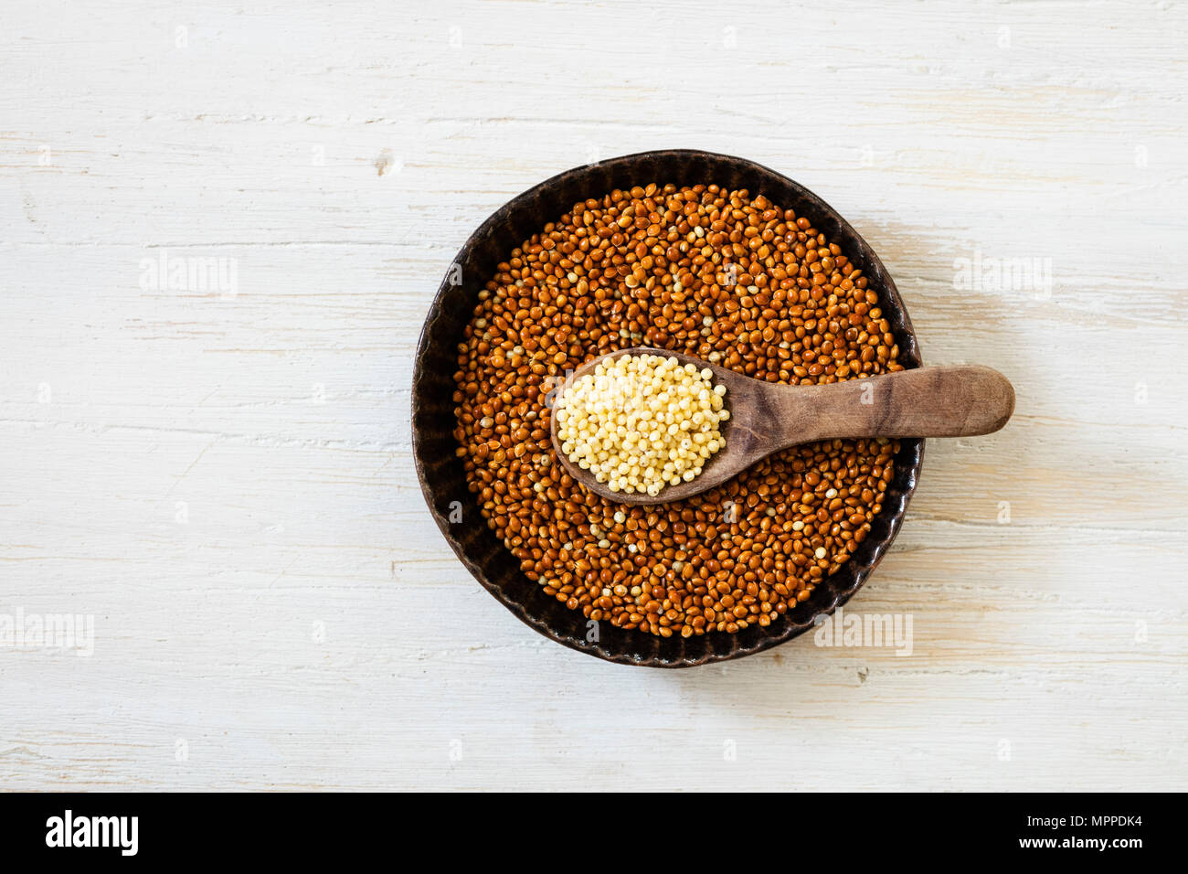 Bowl of brown millet and spoon of Golden millet Stock Photo - Alamy