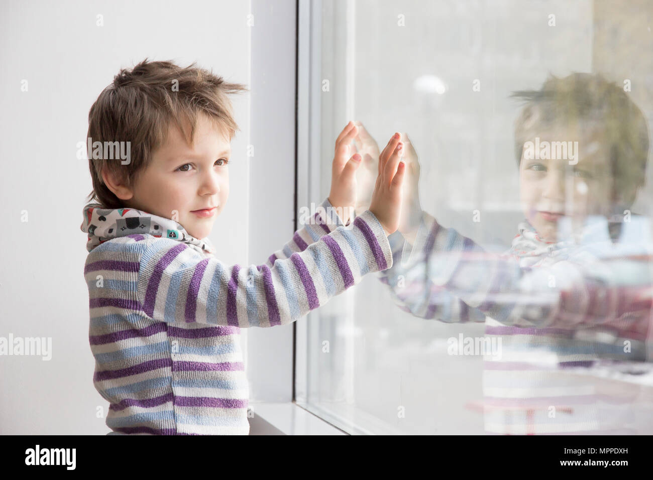 Five-year boy put his hands on window and is reflected in it Stock ...