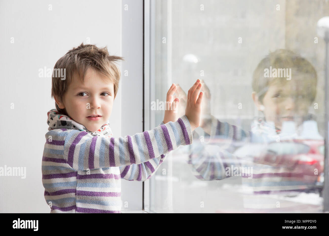Boy leaned his hands to window and looks at us Stock Photo - Alamy