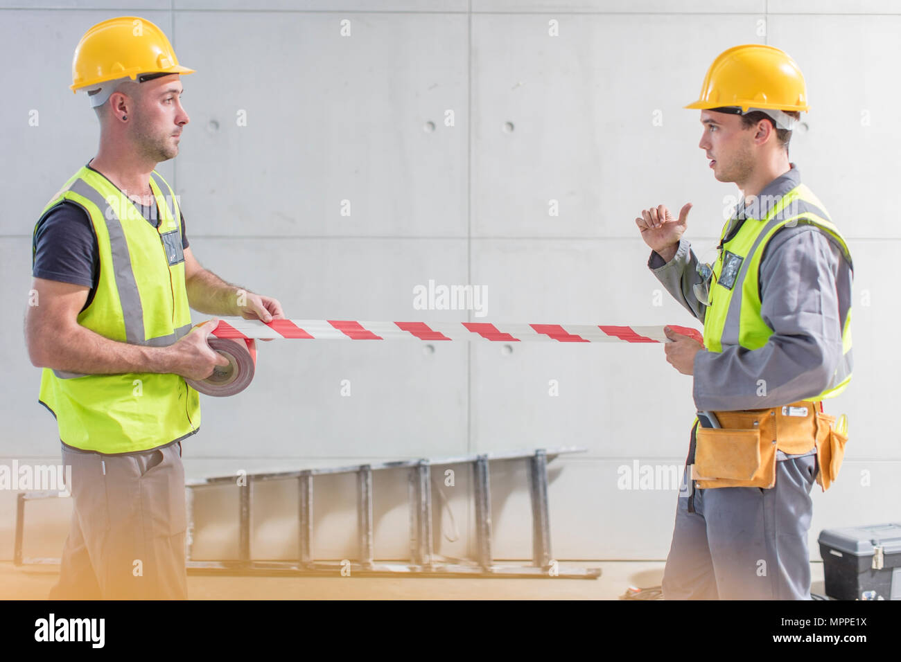 Construction workers using tape on construction site Stock Photo - Alamy