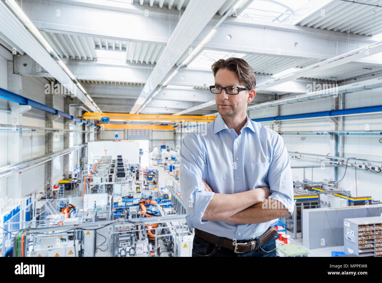 Confident businessman on factory shop floor looking around Stock Photo ...