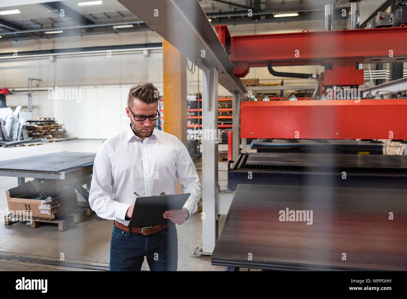 Man writing on clipboard on factory shop floor Stock Photo - Alamy