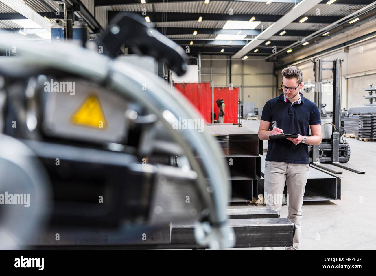 Man writing on clipboard on factory shop floor Stock Photo - Alamy