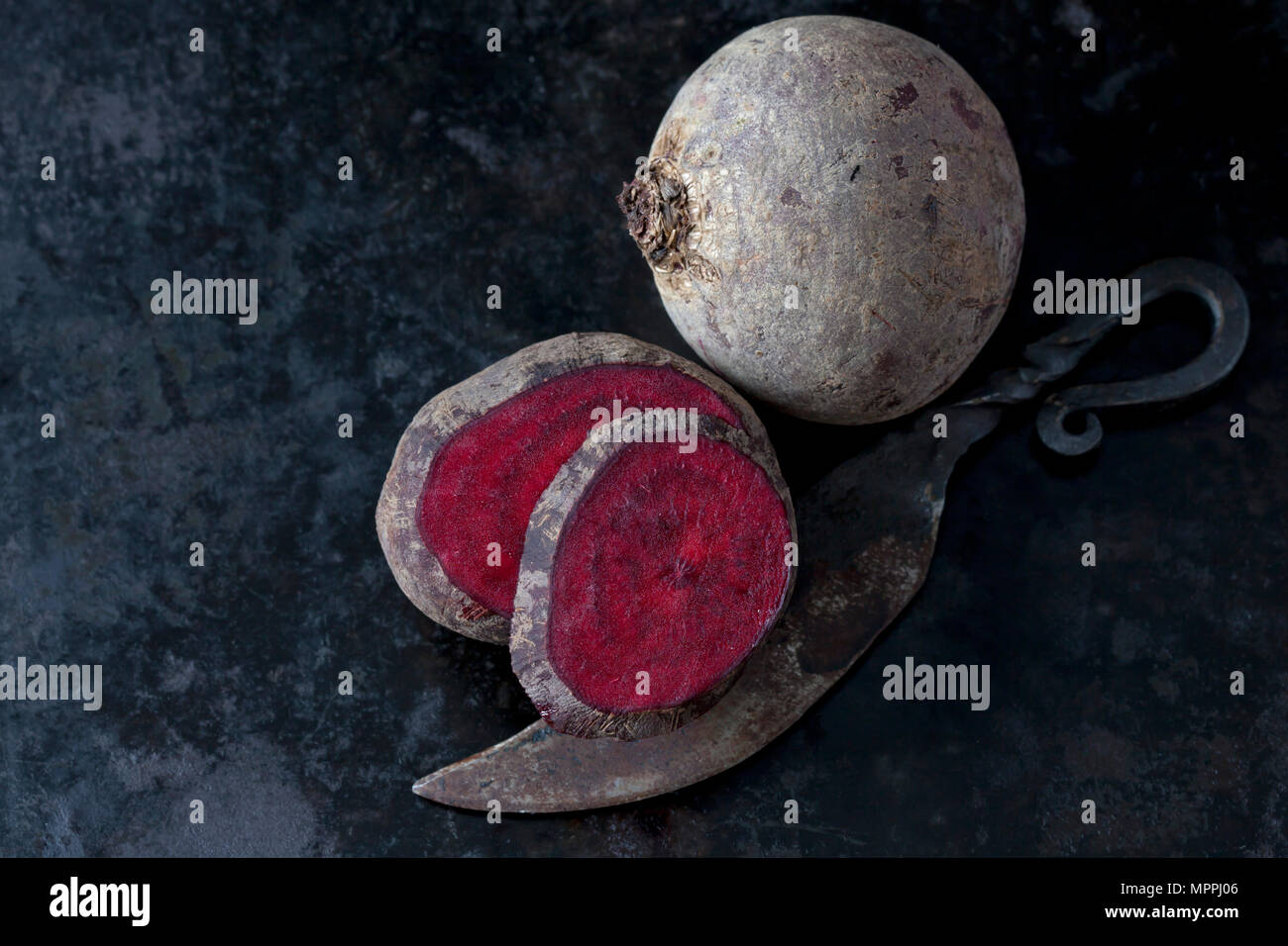 Whole and sliced beetroot and an old knife on dark metal Stock Photo ...
