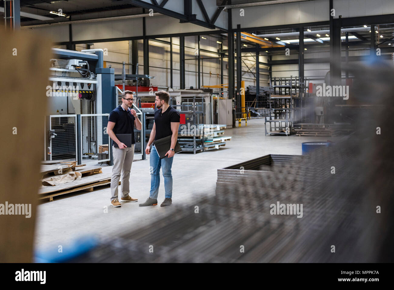 Two men talking on factory shop floor Stock Photo - Alamy