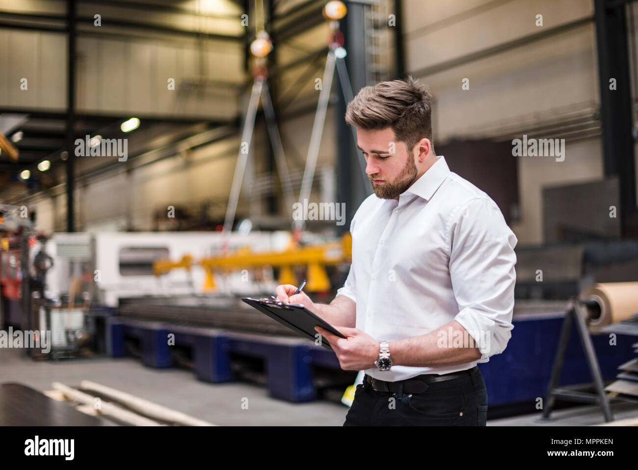 Man writing on clipboard on factory shop floor Stock Photo - Alamy