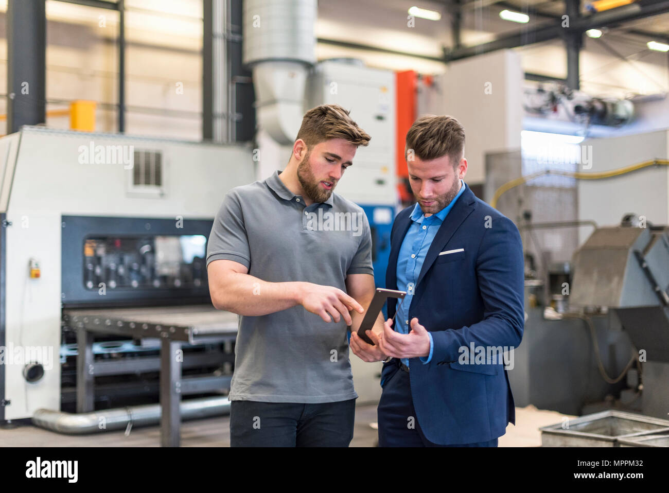 Employee explaining workpiece to businessman on factory shop floor ...