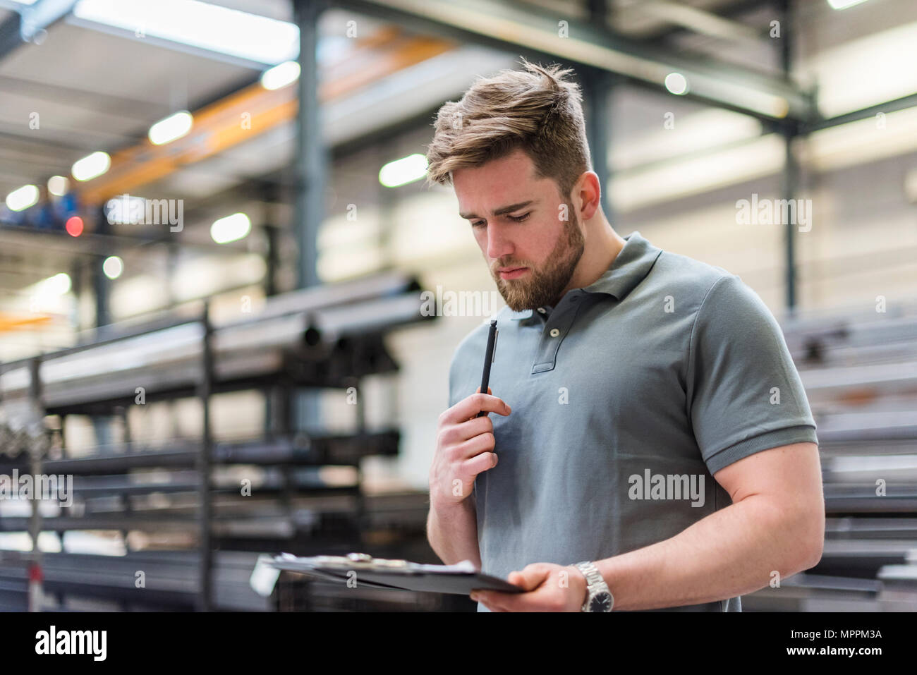 Man writing on clipboard on factory shop floor Stock Photo - Alamy