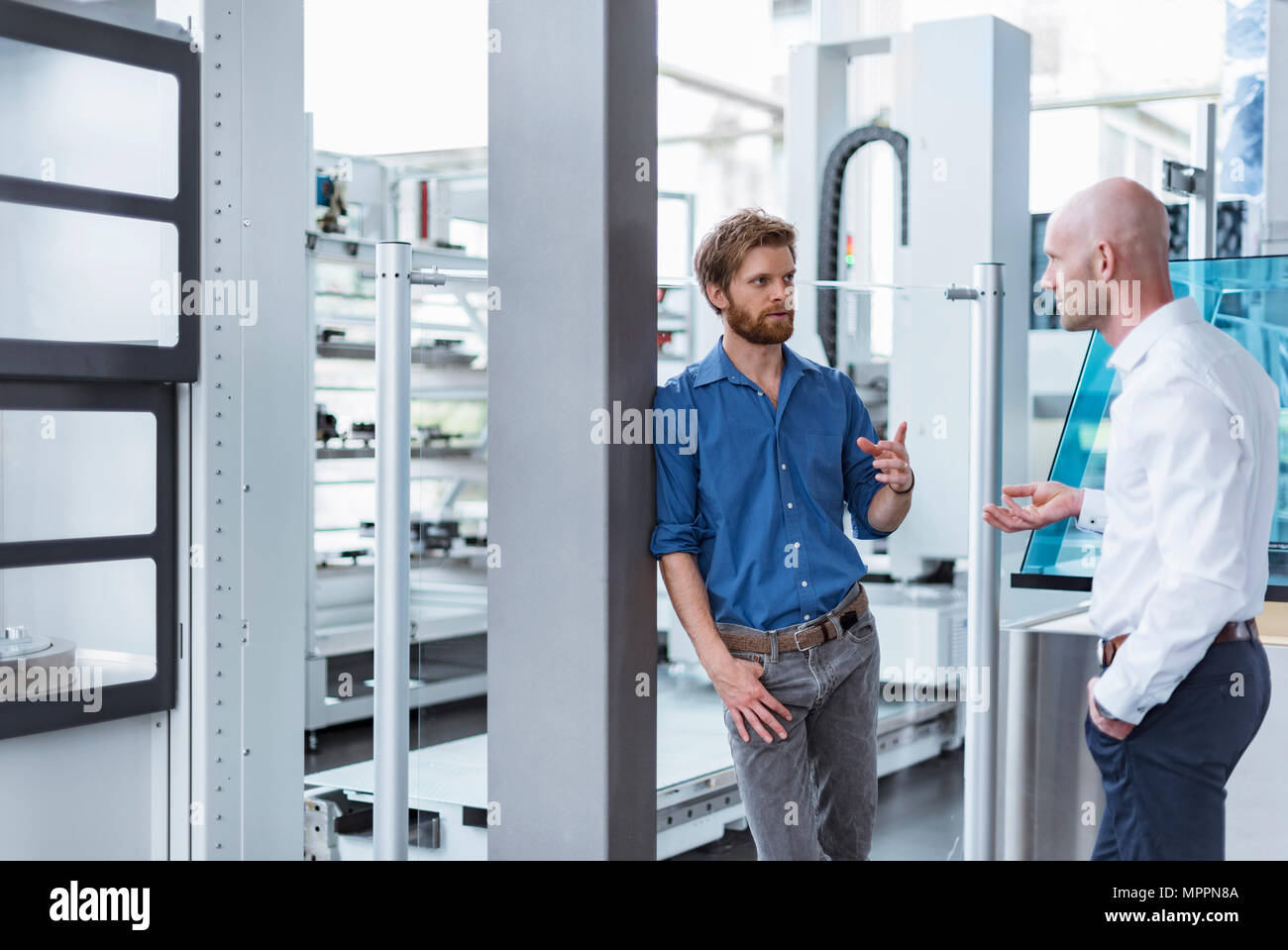 Two men talking in modern factory Stock Photo - Alamy