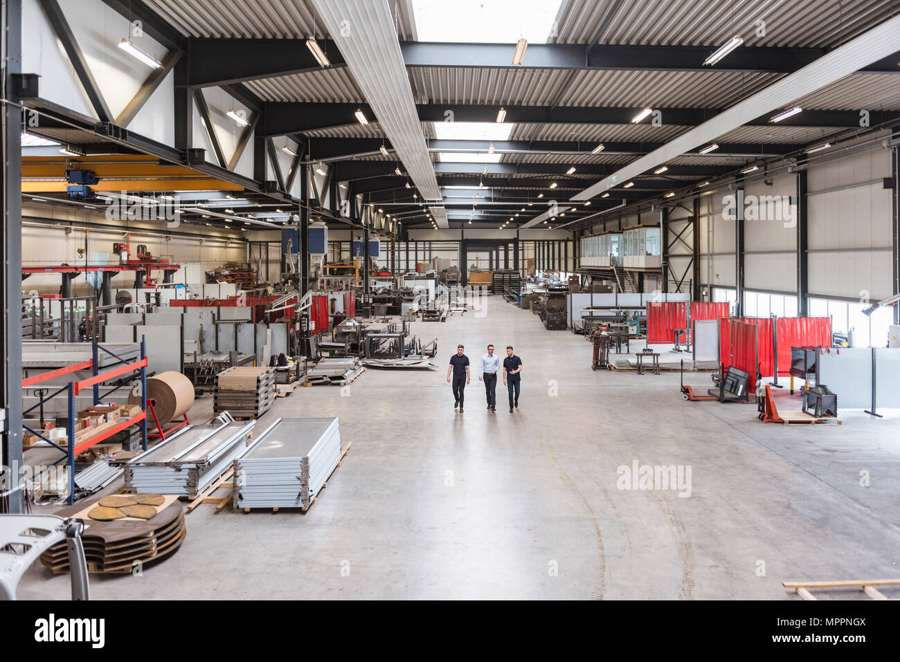 Three men walking and talking on factory shop floor Stock Photo - Alamy
