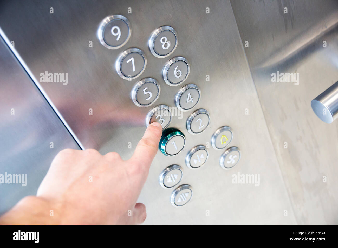 Finger presses on third floor of modern office building elevator metal ...