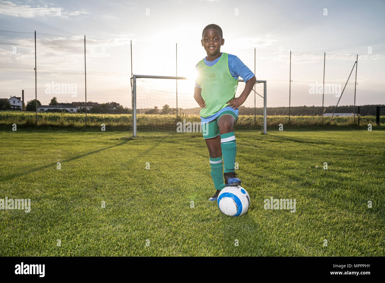 Portrait of confident young football player with ball on football ...