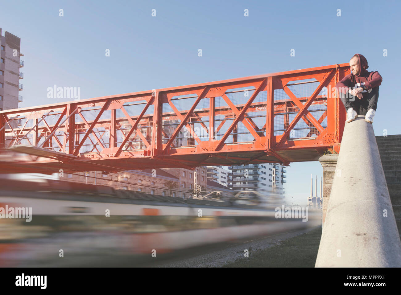 Man sitting on wall, next to passing train Stock Photo - Alamy