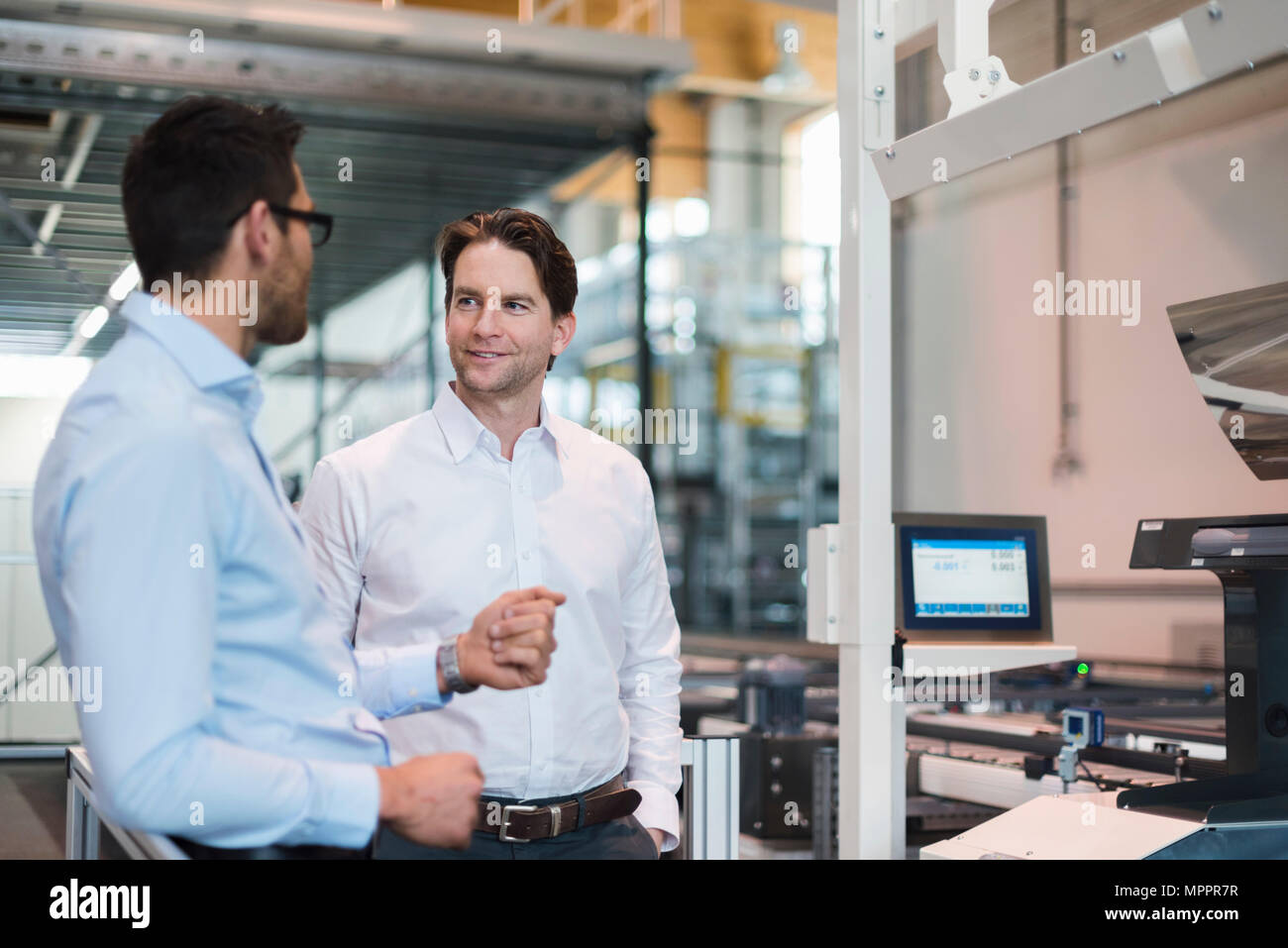 Two businessmen talking in modern factory Stock Photo - Alamy