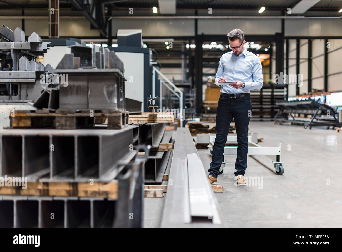 Man with tablet standing on factory shop floor Stock Photo - Alamy