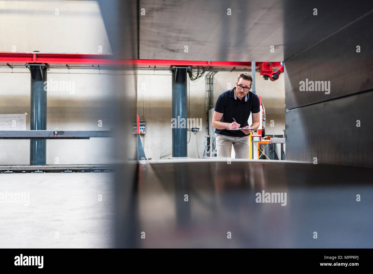 Man writing on clipboard on factory shop floor Stock Photo - Alamy
