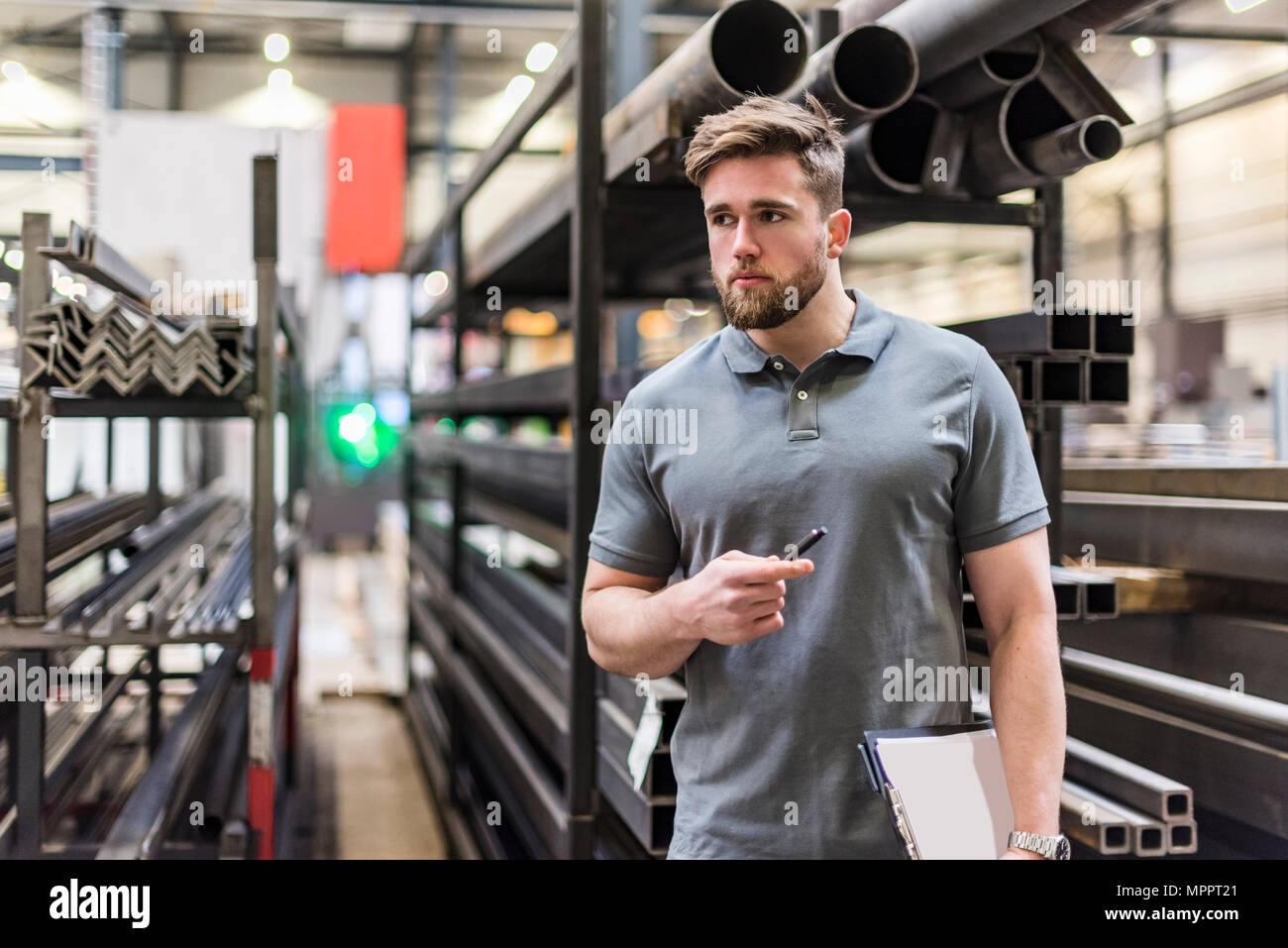 Man with clipboard on factory shop floor looking around Stock Photo - Alamy