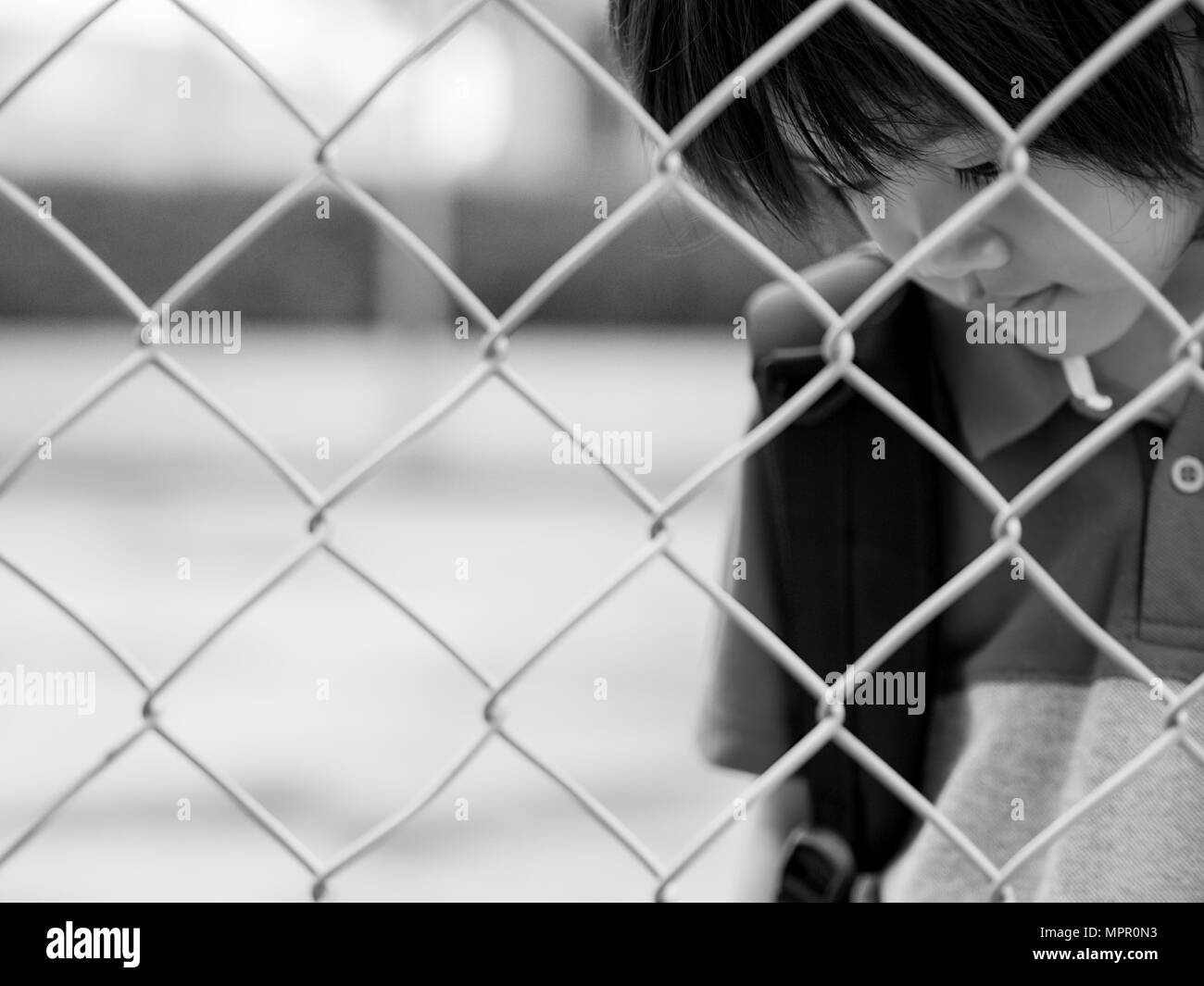 Black and white sad boy behind fence mesh netting. Emotions concept ...