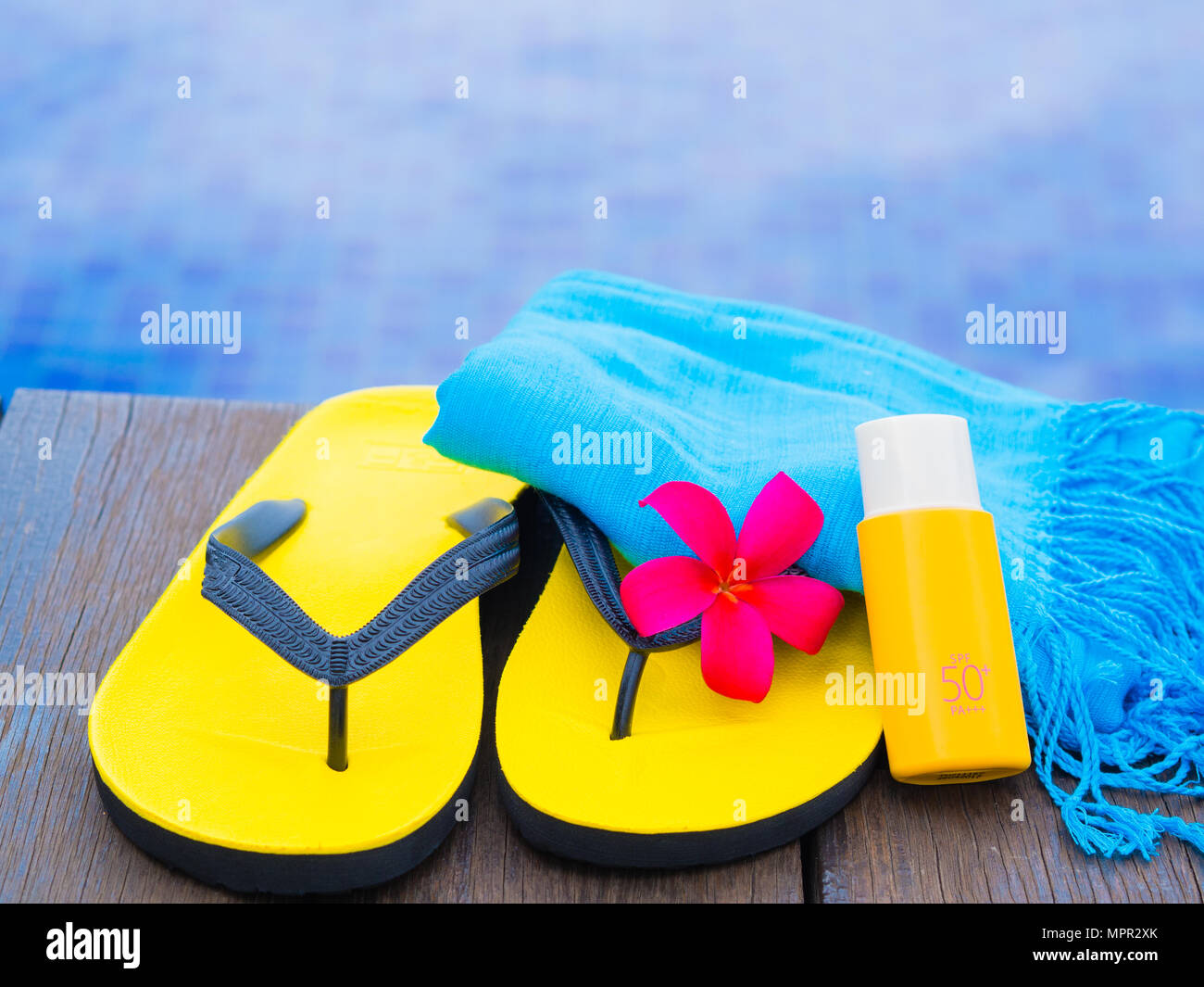 Sunscreen lotion with flip flops and red frangipani (plumeria) flowers ...