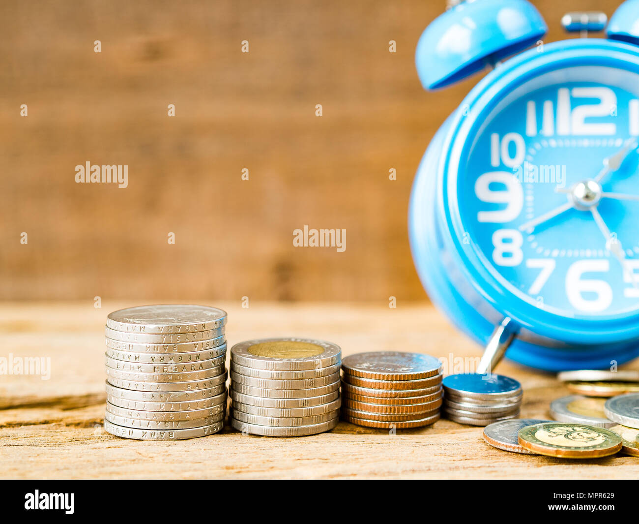 Stack of coins and alarm clock on wooden background. Business Finance ...