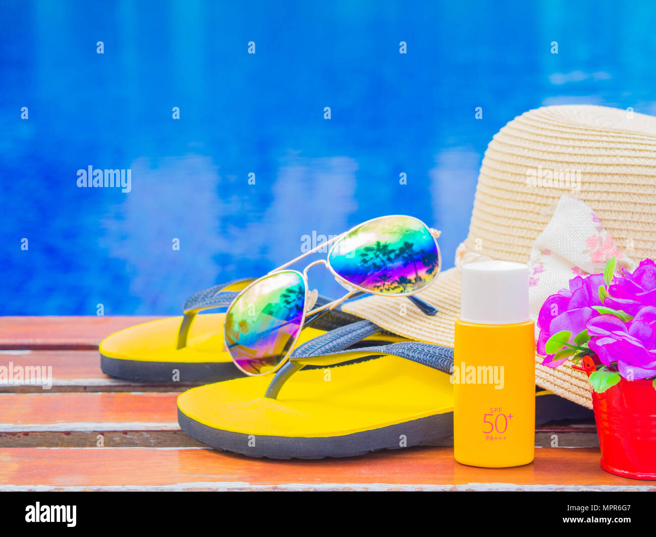 Sunglasses with summer hat, flip flops, shampoo, sunscreen lotion and ...