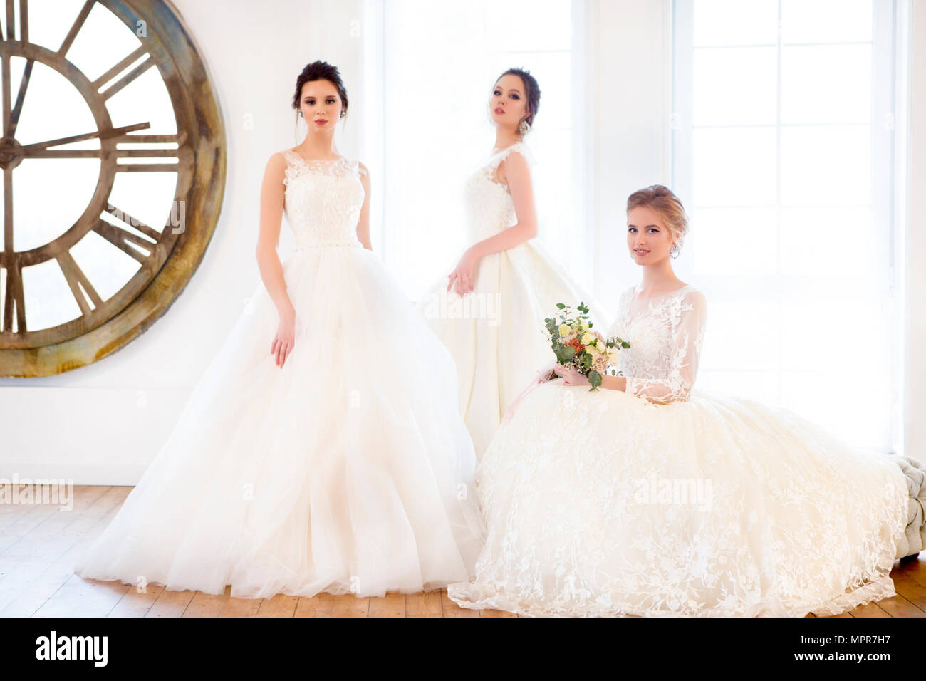 Three young woman with bouquets wearing wedding dresses Stock Photo - Alamy
