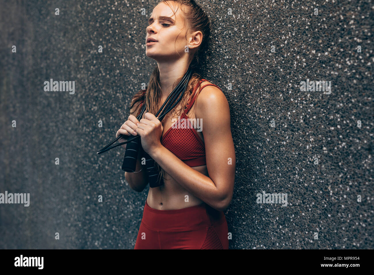 fitness woman leaning to a wall after skipping rope workout. Female ...